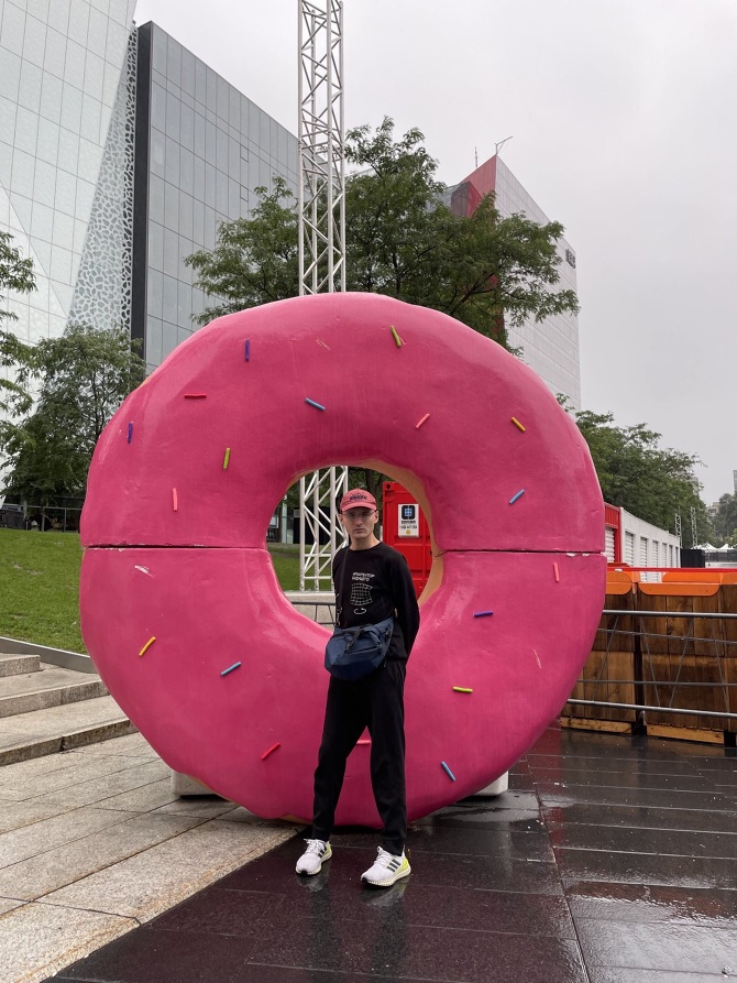 Outdoor installation of oversized pink donut sculpture with person ...